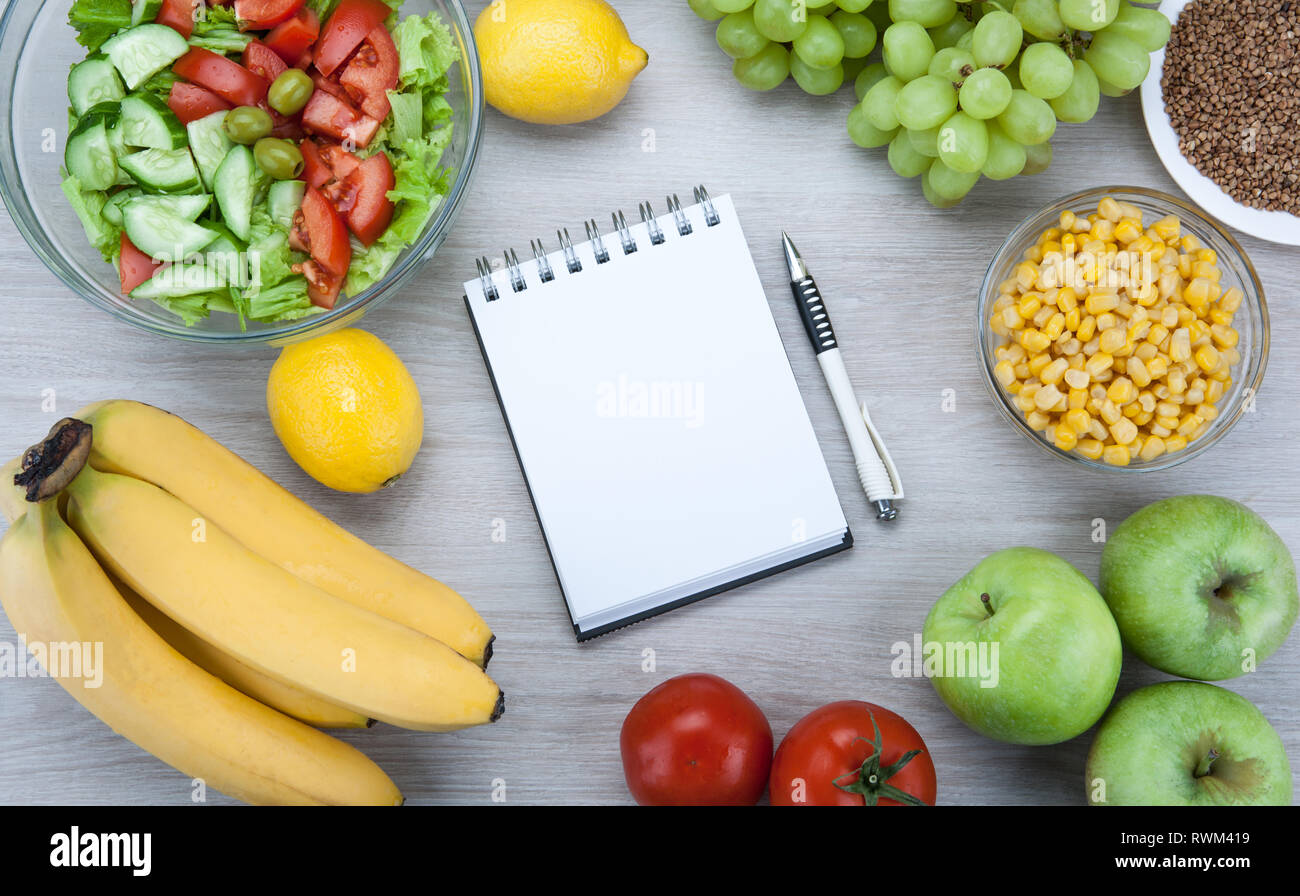 notebook with a diet plan with fresh vegetables and fruits on the table ...