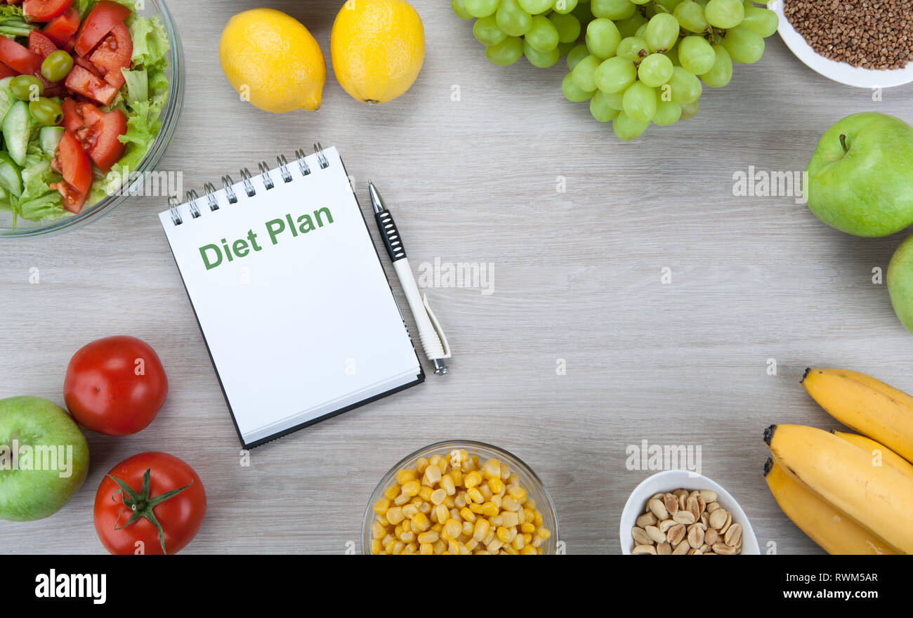notebook with a diet plan with fresh vegetables and fruits on the table ...