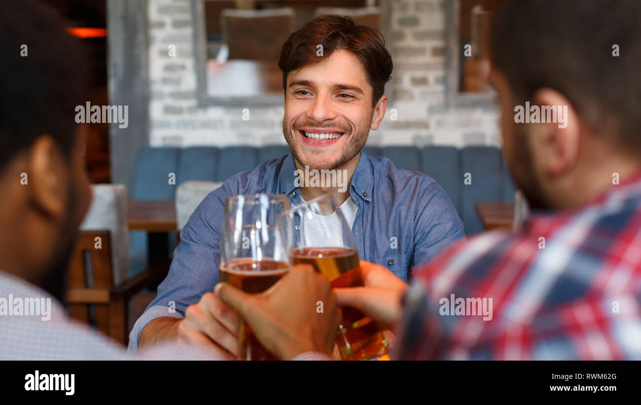 Friends drinking beer, celebrating meeting in bar Stock Photo - Alamy