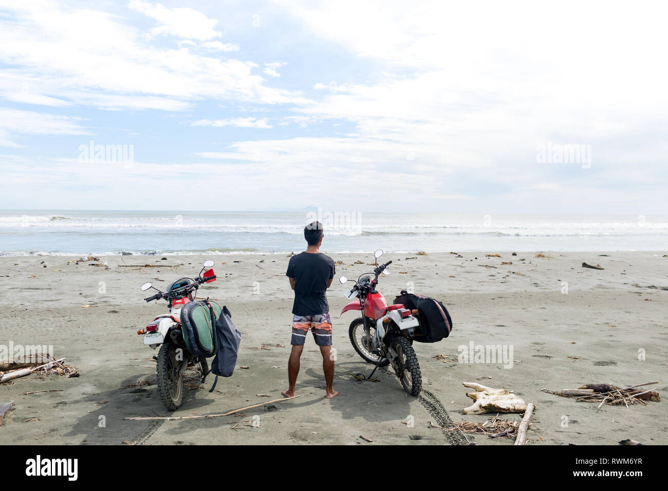 Motorcyclist carrying surfboard on sandy beach, Abulug, Cagayan ...