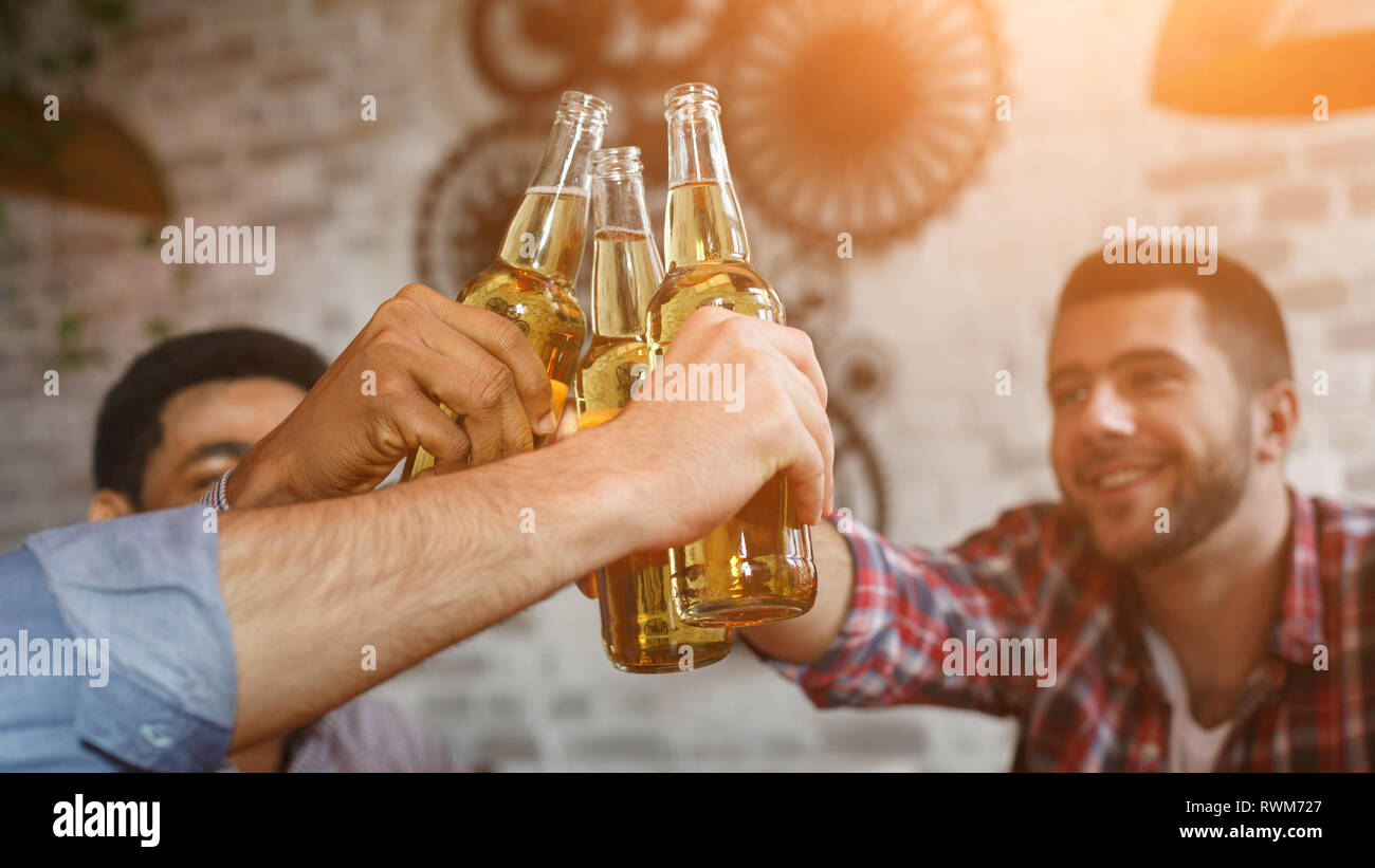 Clink beer bottles. Friends resting together in bar Stock Photo - Alamy