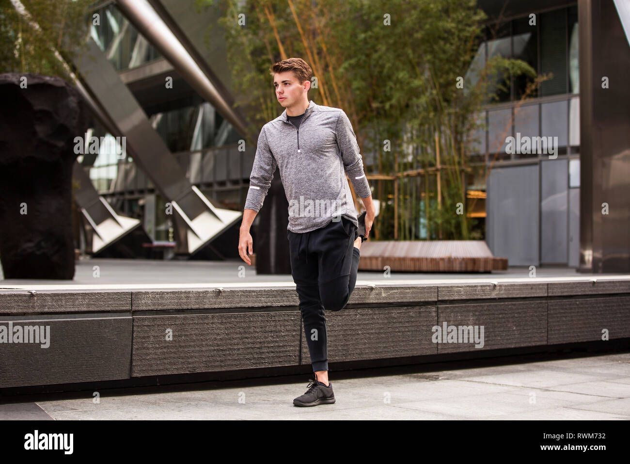 Young runner stretching on pavement, London, UK Stock Photo - Alamy