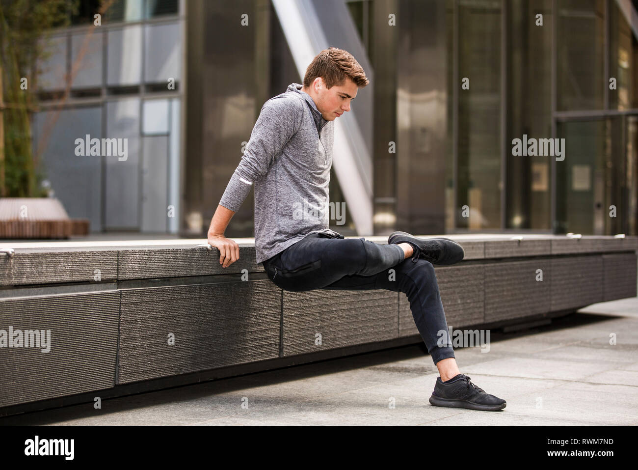 Young runner stretching on pavement, London, UK Stock Photo - Alamy