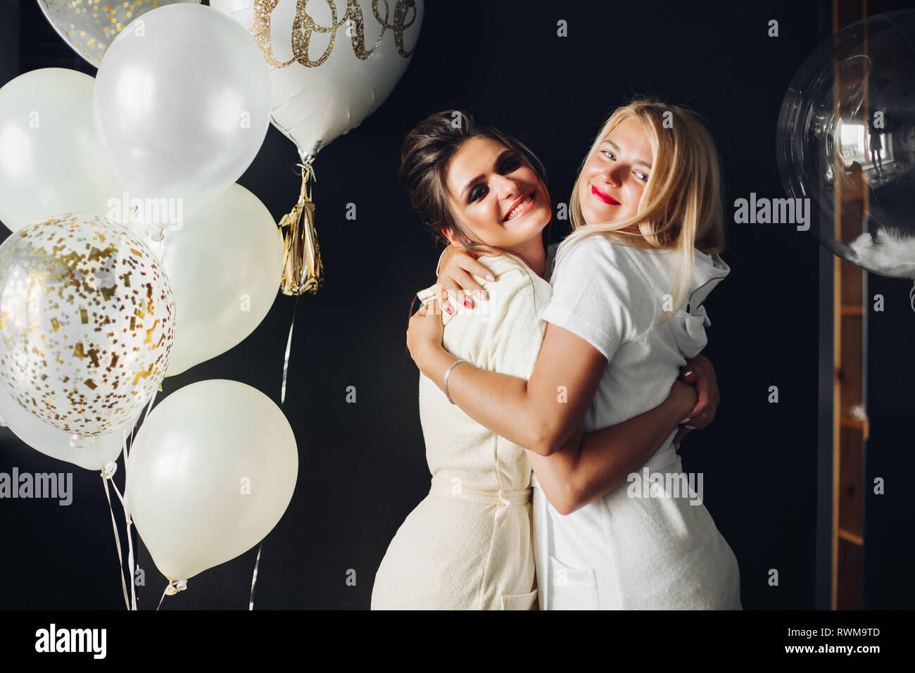 Happy bride hugging with bridesmaid and looking at camera Stock Photo ...