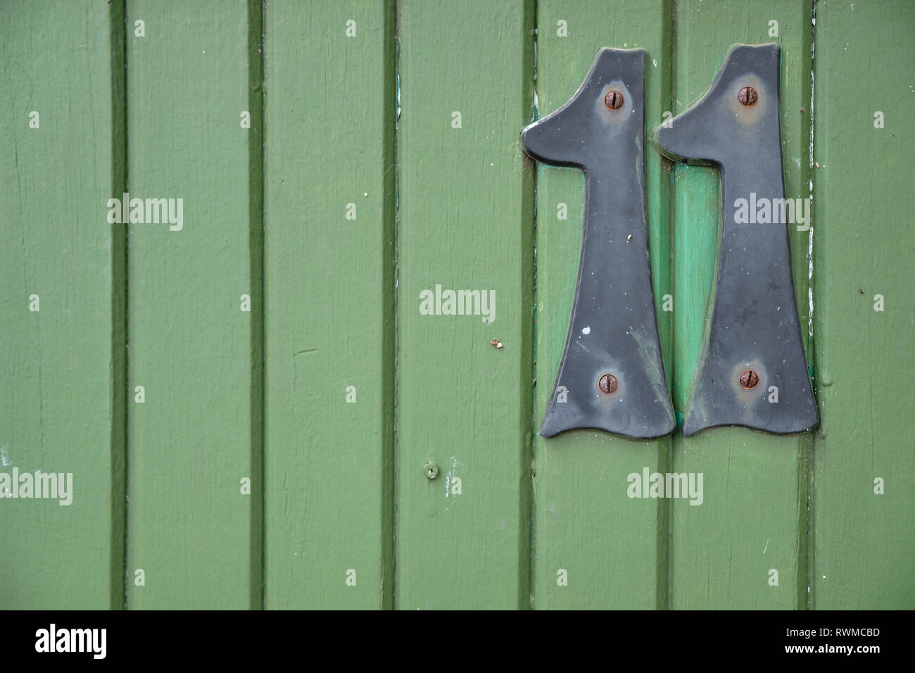 Number 11 on forest green wood panel fence, with a screw in the middle ...