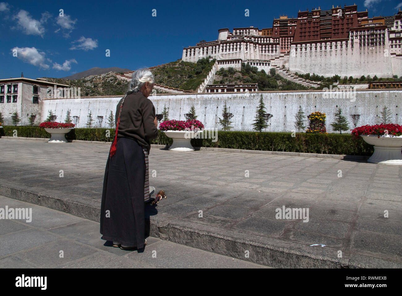 A Tibetan woman prepares to bow and prostrate herself in front of the ...