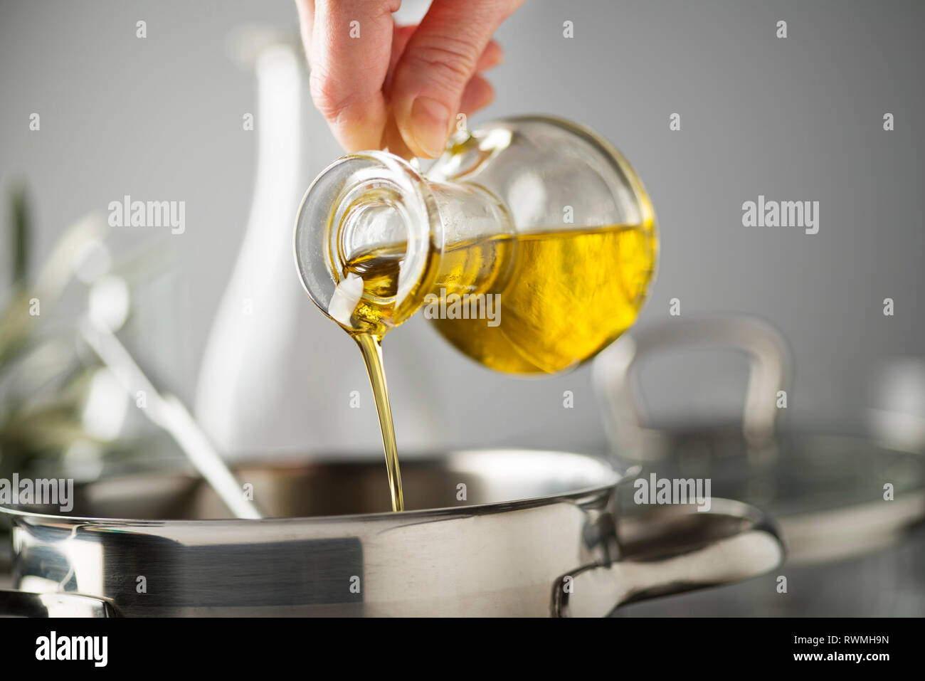 Cooking meal in a pot. Bottle of Extra virgin oil pouring in to pot for ...