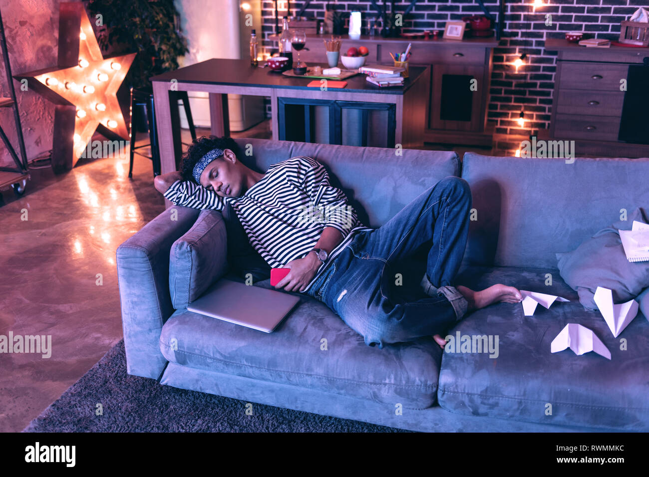 African American guy sitting up at the laptop until late and dozing off ...