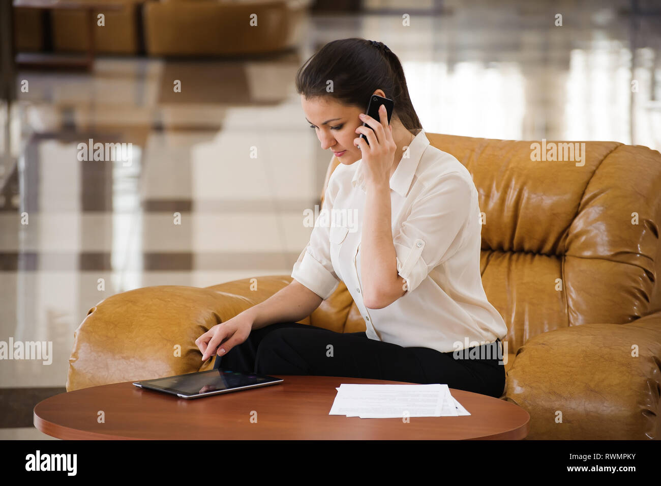 Portrait of busy business woman working while sitting at sofa Stock ...