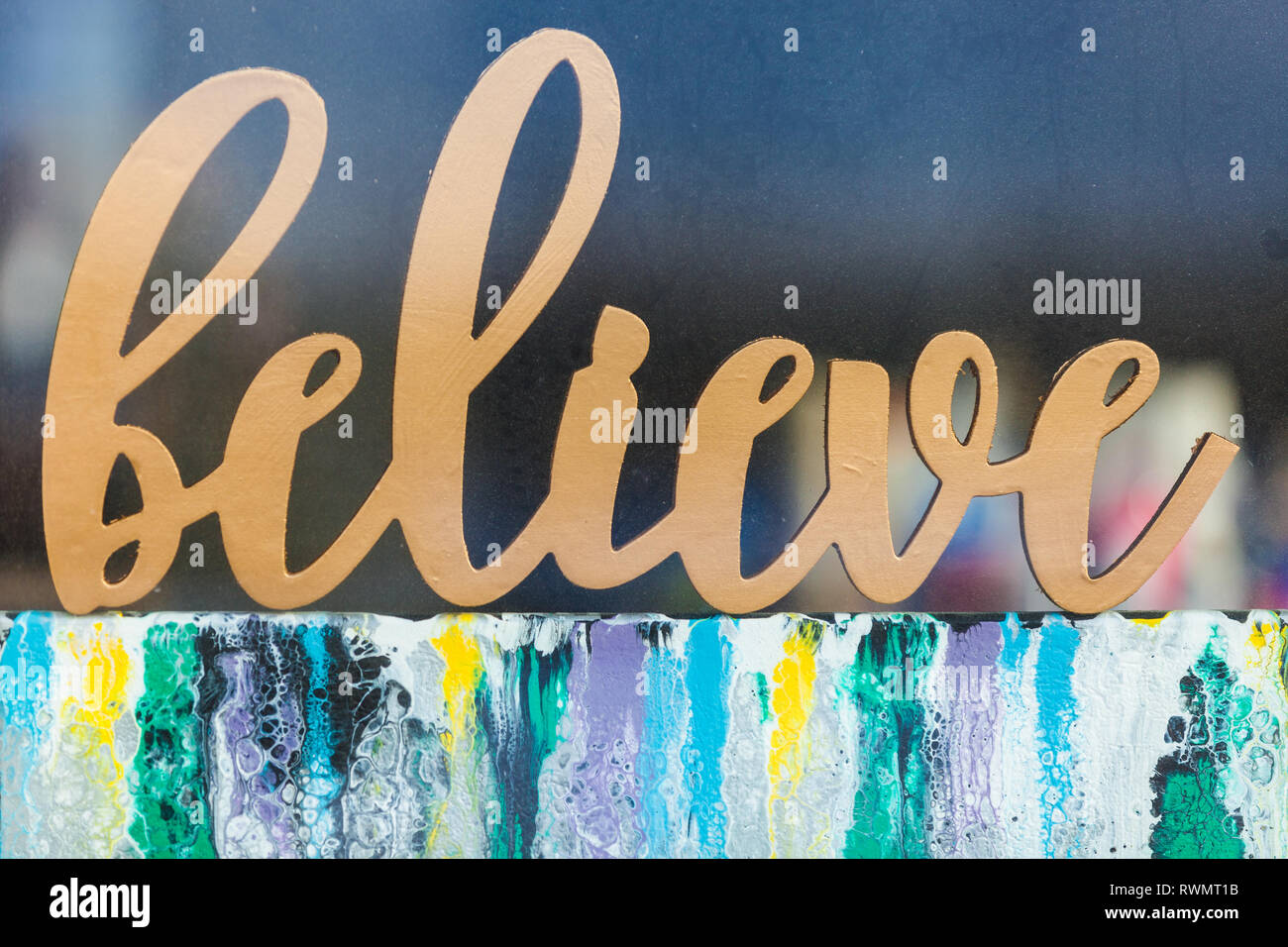 The word BELIEVE mounted atop a painted panel Stock Photo - Alamy