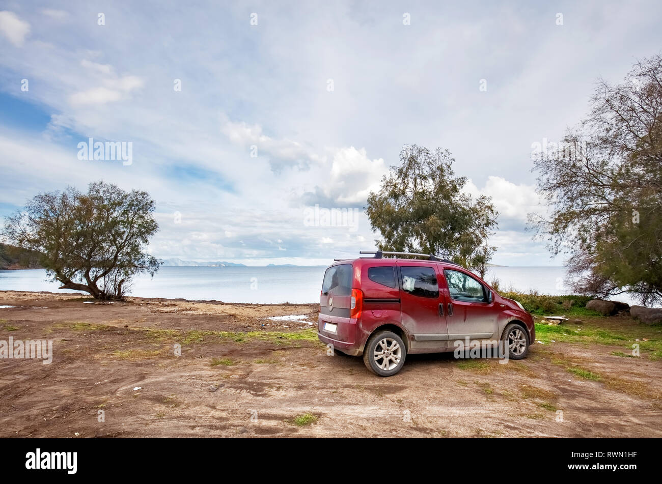 Red transporter car parked on a muddy soil ground near the seashore on ...
