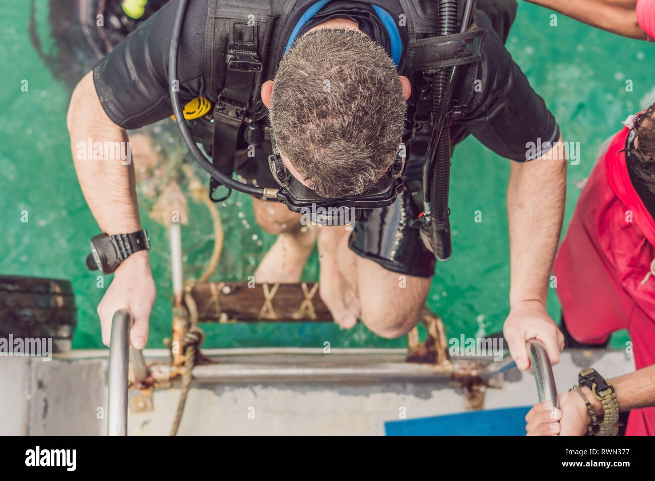 Happy diver returns to the ship after diving Stock Photo - Alamy