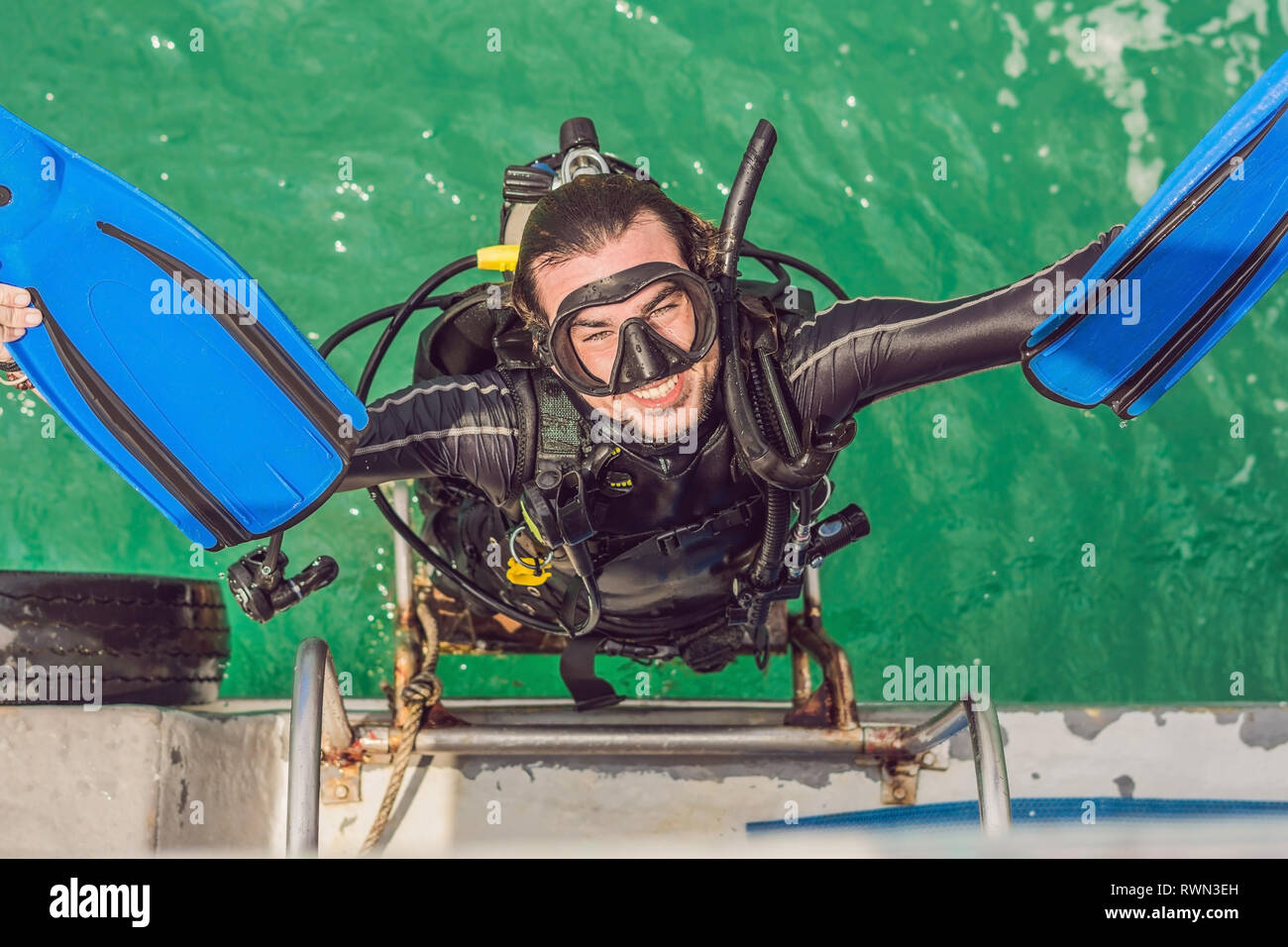 Happy diver returns to the ship after diving Stock Photo - Alamy