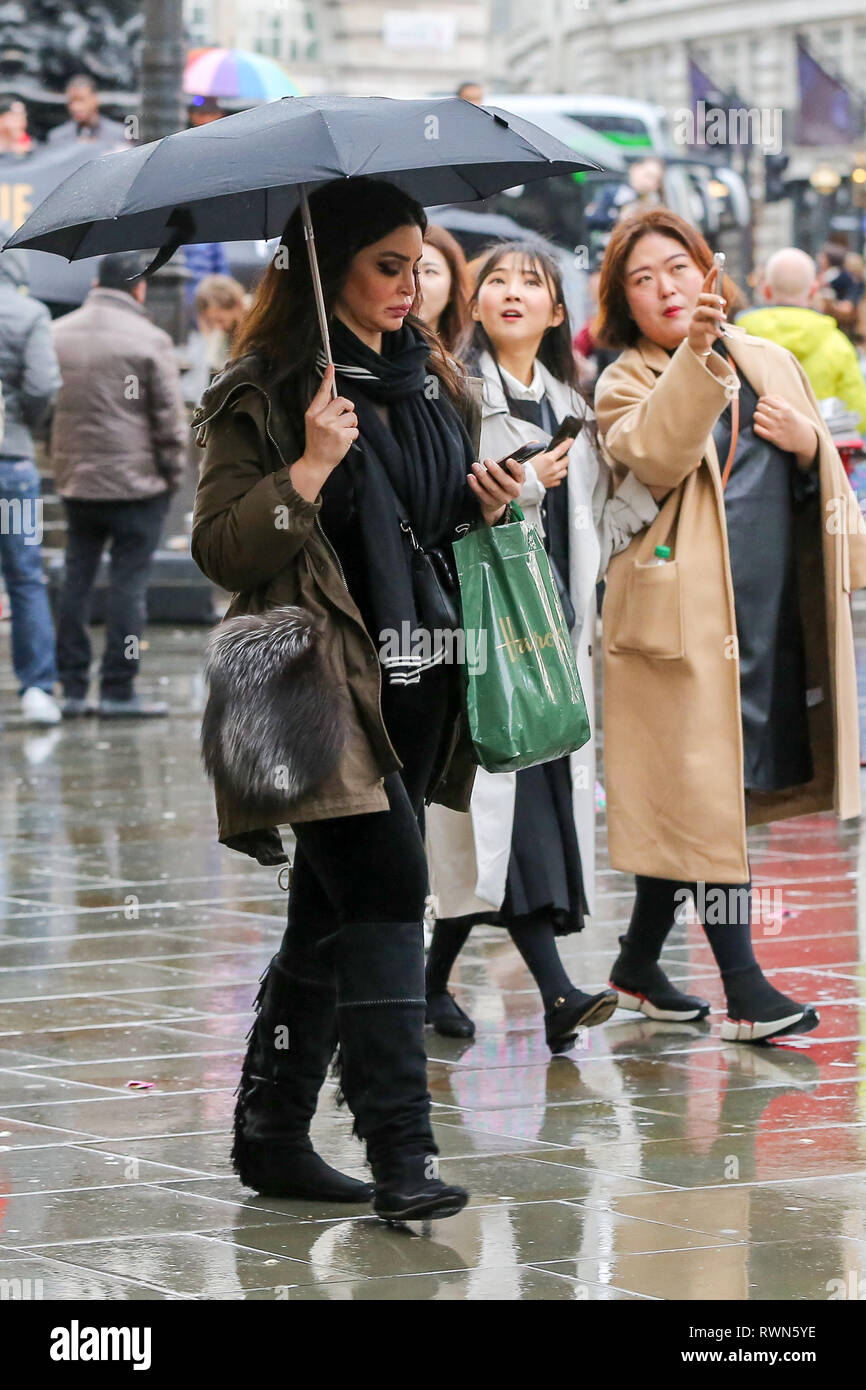 Tourists are seen sheltering from the rain beneath an umbrella during ...