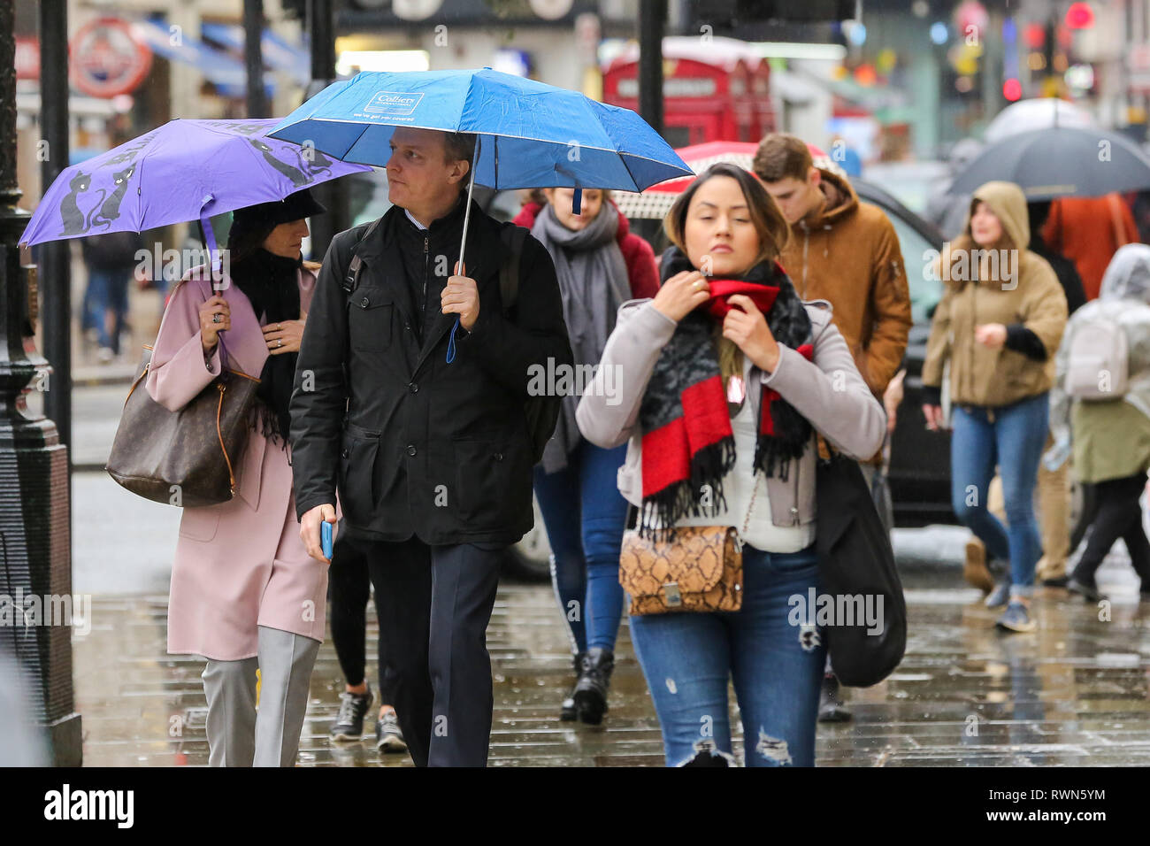 Tourists are seen sheltering from the rain beneath an umbrella during ...