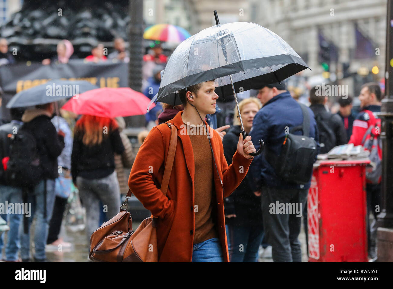 A man is seen sheltering from the rain beneath an umbrella during rainy ...
