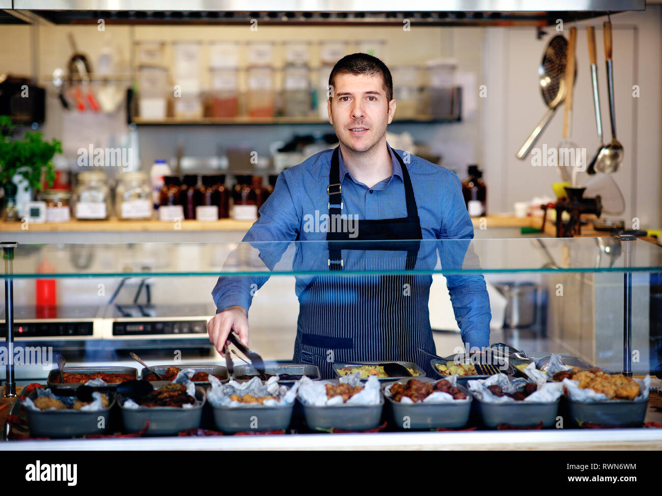 Young business owner standing behind the counter of his restaurant ...