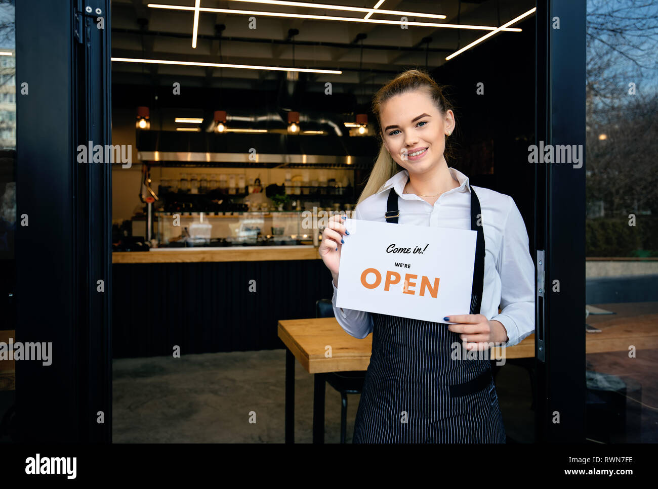 Portrait of a happy waitress standing at restaurant entrance. Portrait ...