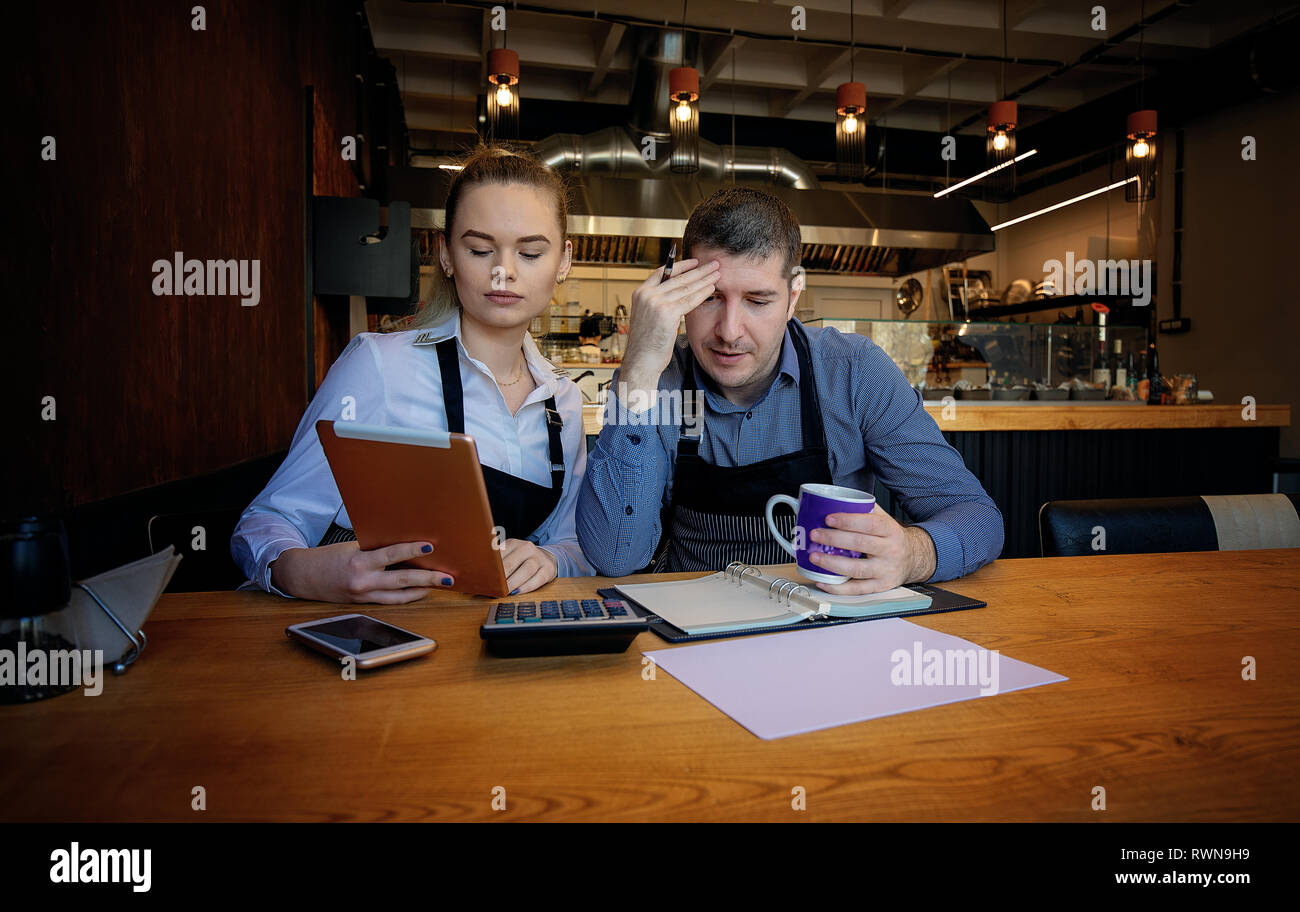Young entrepreneurs looking over documents. At a table, in the ...