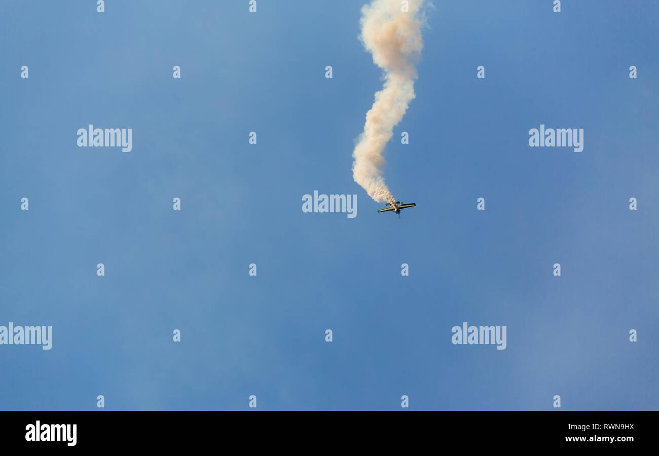 Unidentifiable single airplane performing acrobatic flight on blue sky ...
