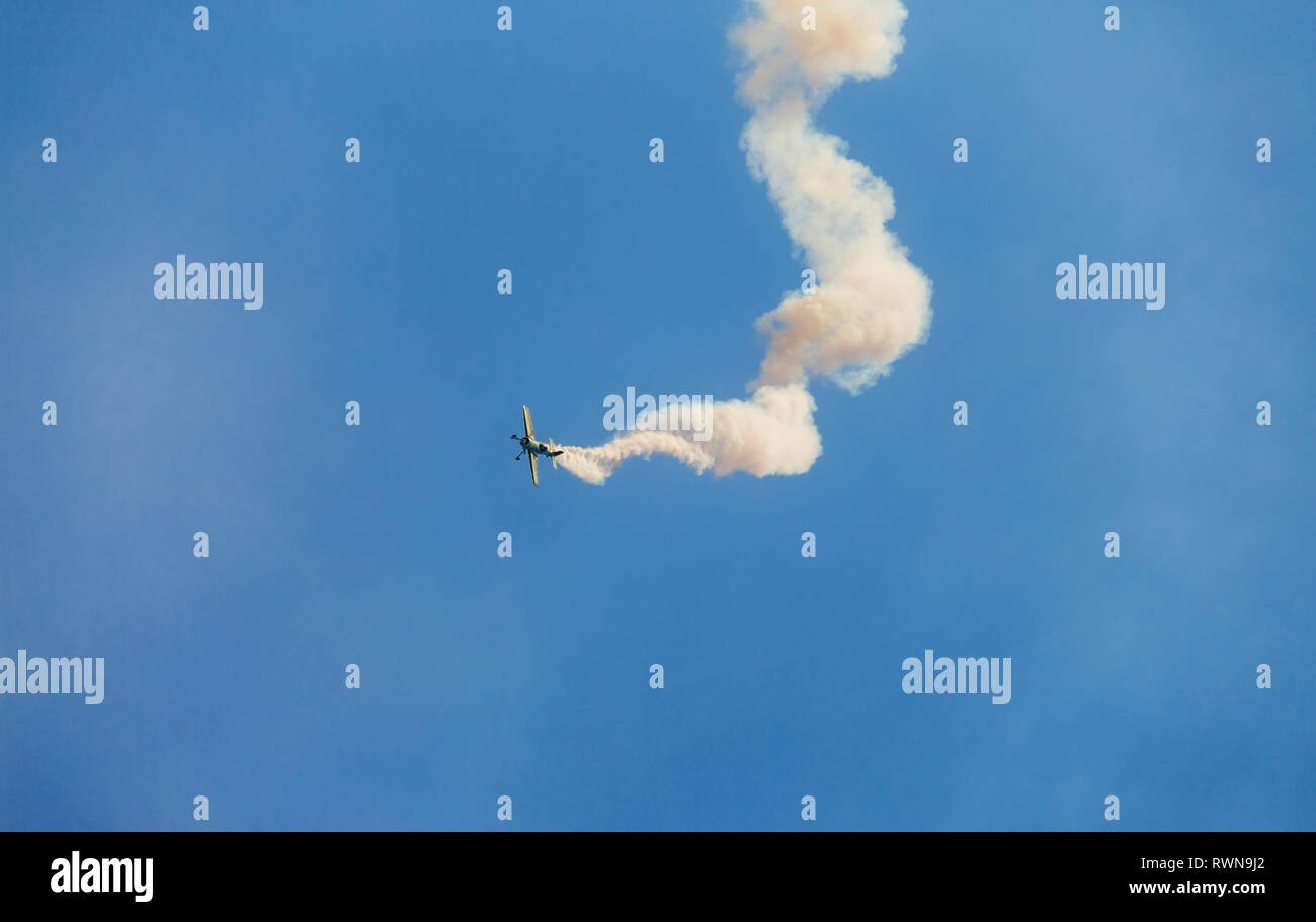 Unidentifiable single airplane performing acrobatic flight on blue sky ...