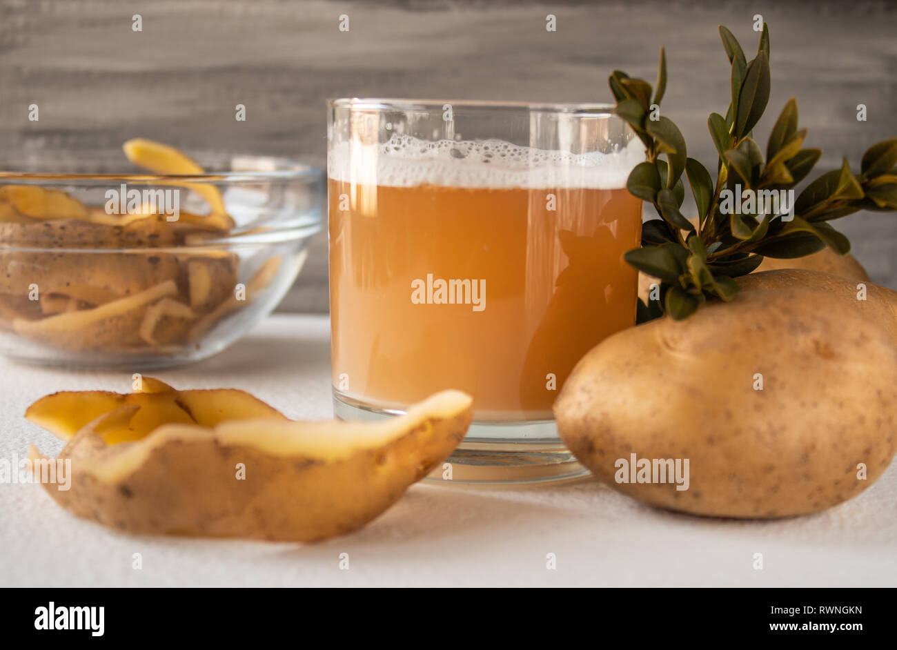 Juice with potatoes in a glass. Peeled potatoes on a white background ...