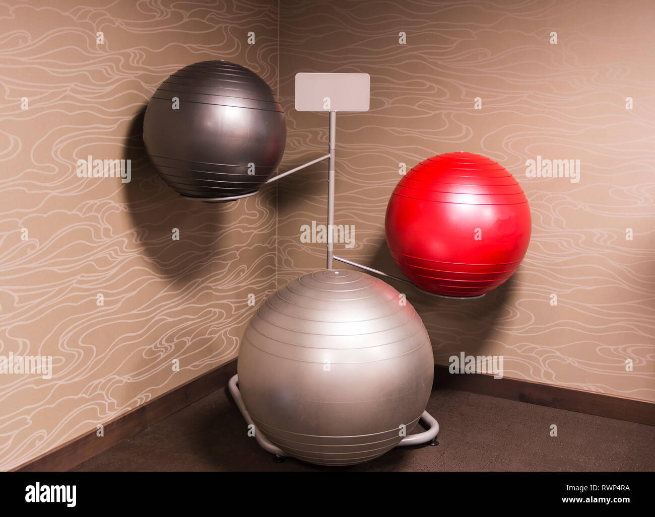 Three different sized exercise balance balls on a rack in the corner of ...