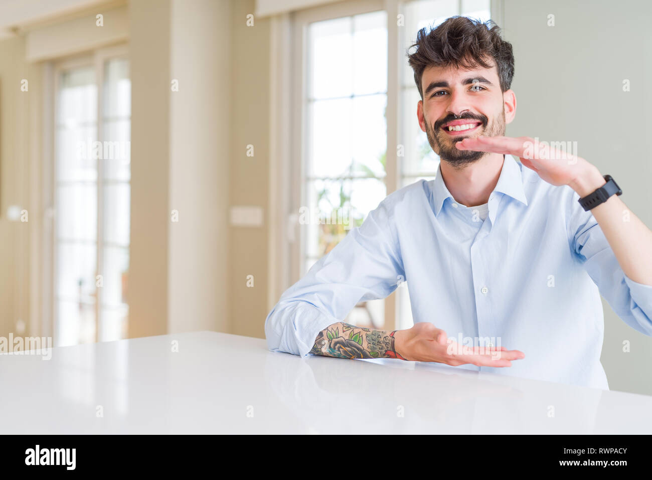 Young businesss man sitting on white table gesturing with hands showing ...