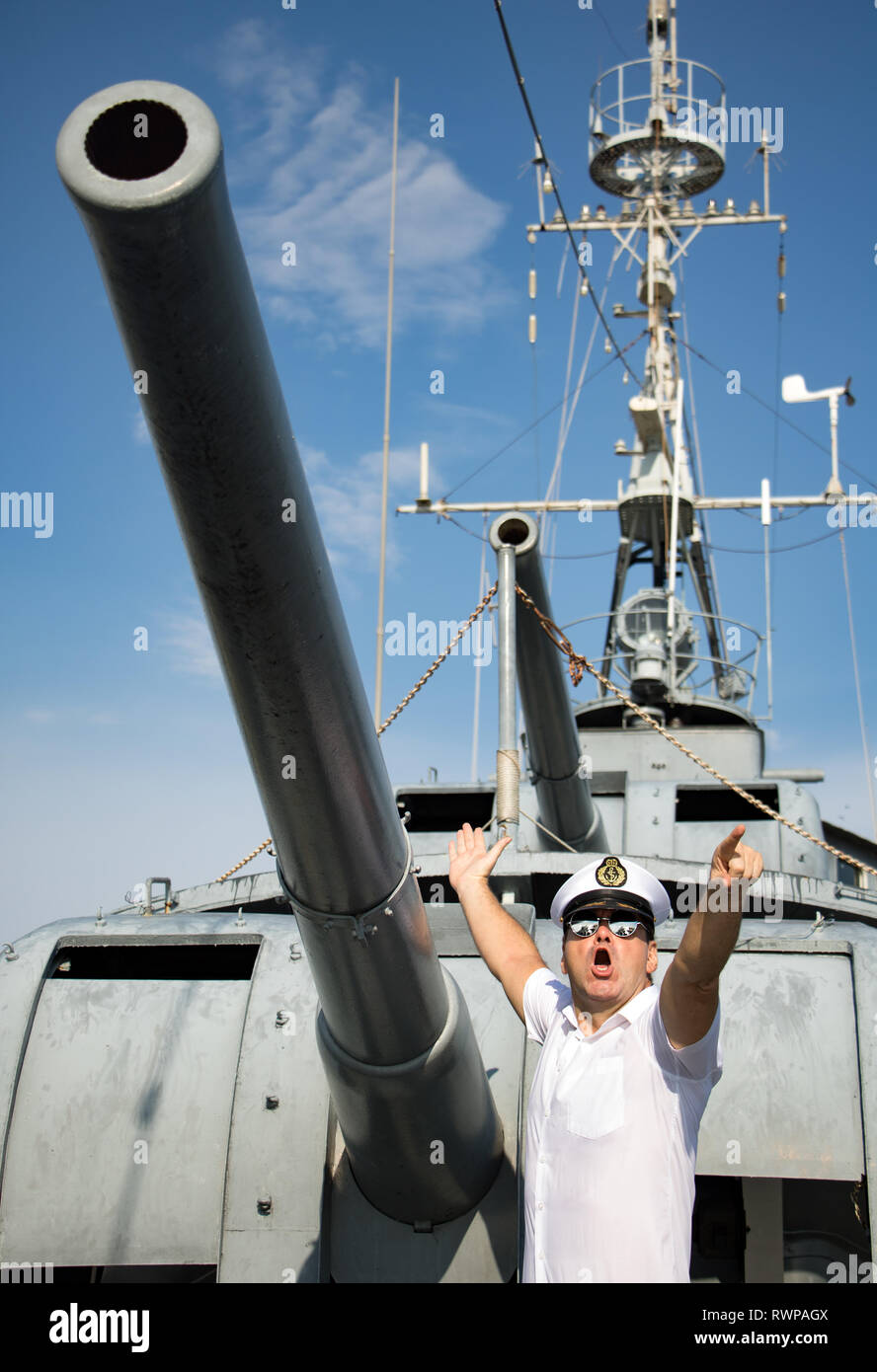 A sailor officer standing beside gun and pointing his finger ahead.The ...