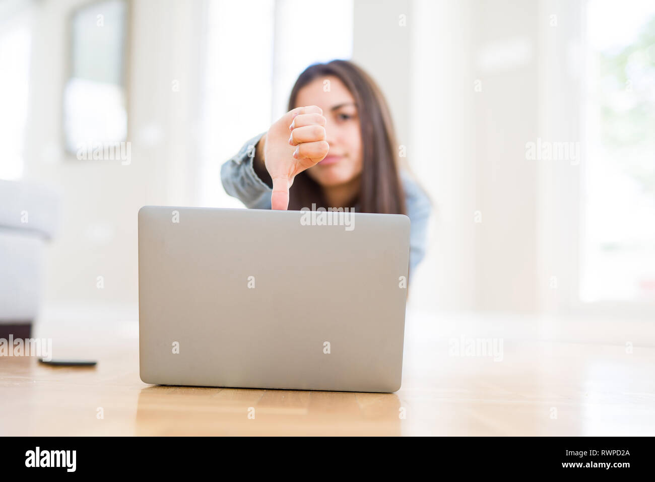 Beautiful young woman laying on the floor using laptop with angry face ...