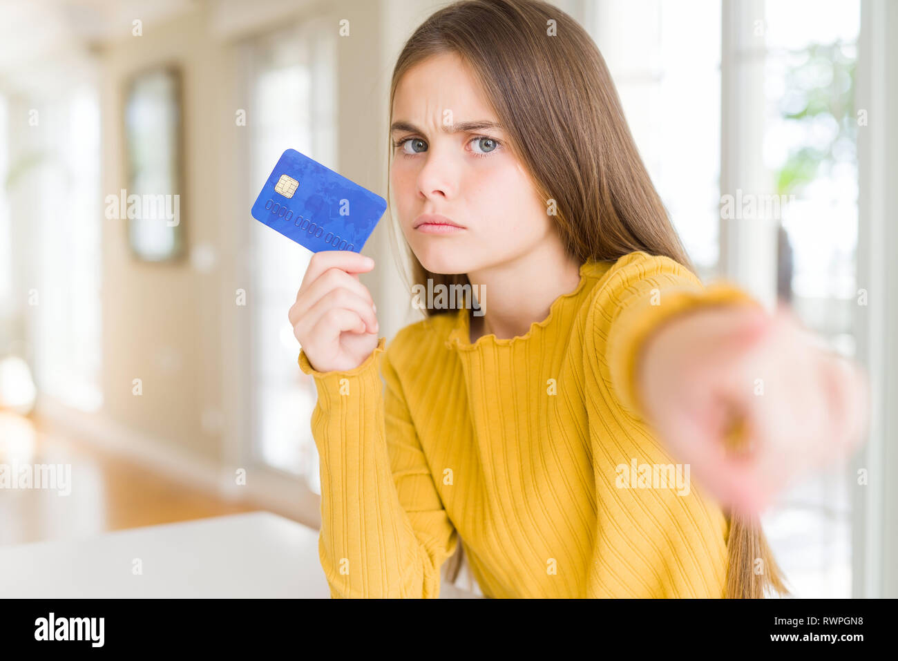 Beautiful young girl kid holding credit card pointing with finger to ...