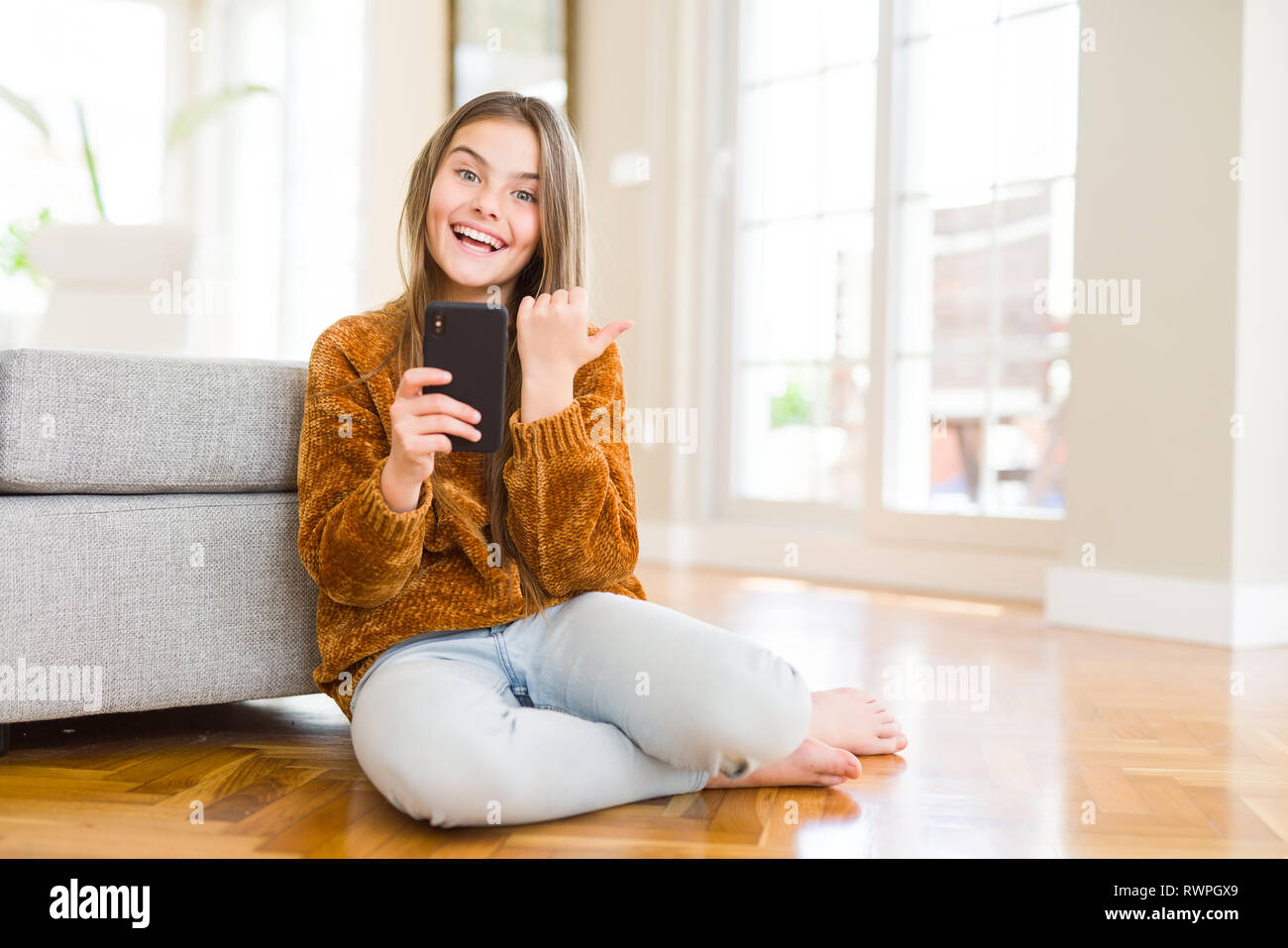 Beautiful young girl kid sending a message using smartphone pointing ...