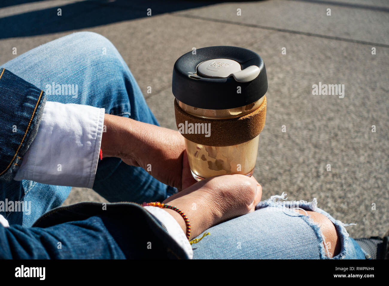 closeup of a young girl hands and wearing ripped jeans holding her ...