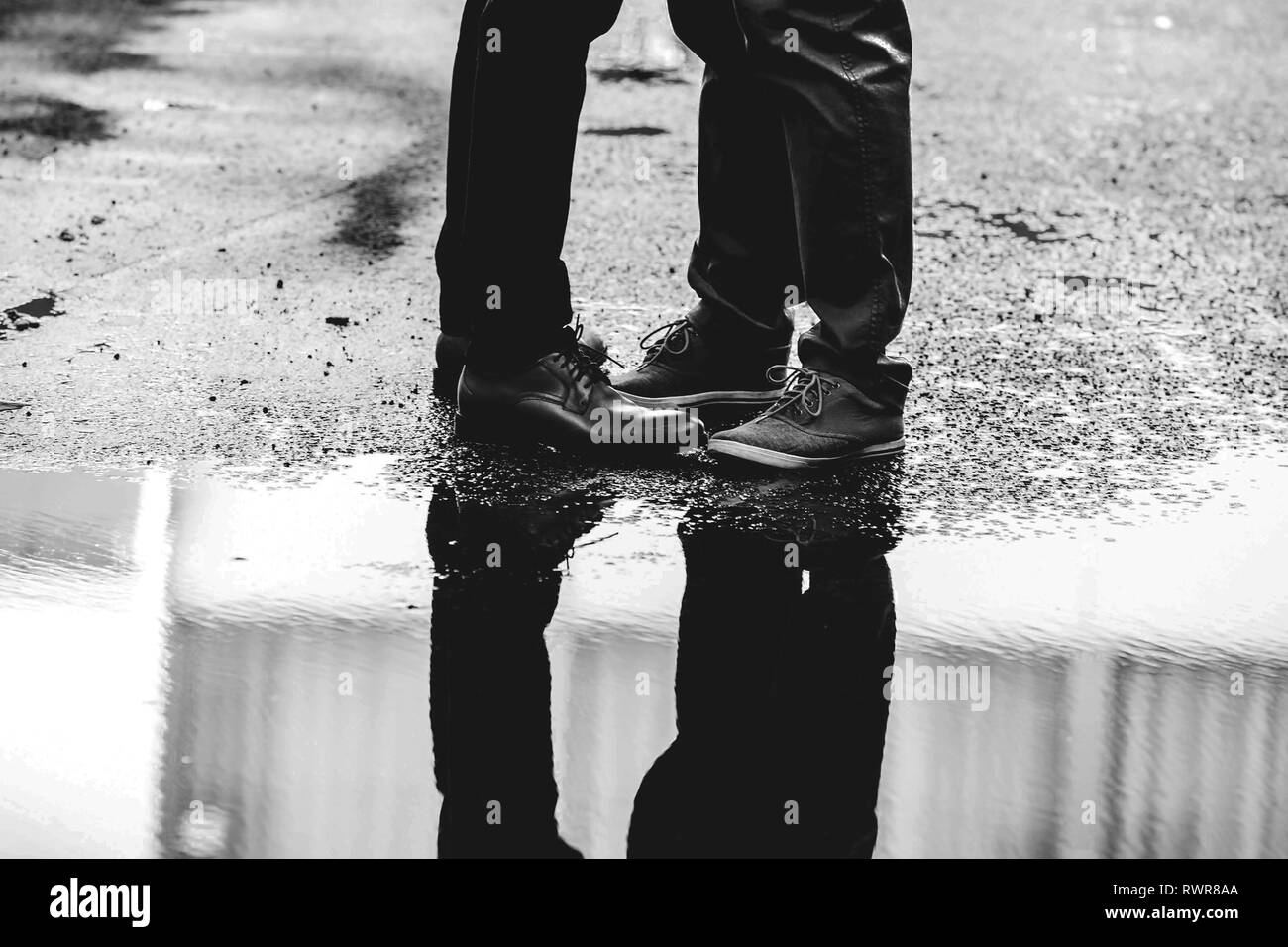 Rain puddle reflection of two people's legs Stock Photo - Alamy