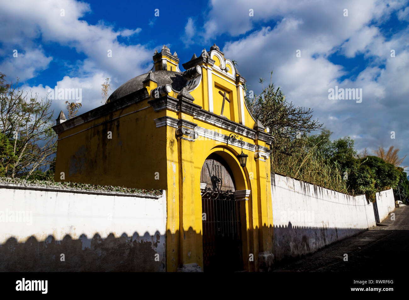 Yellow chapel church with crooked cross under blue cloud sky, Antigua ...