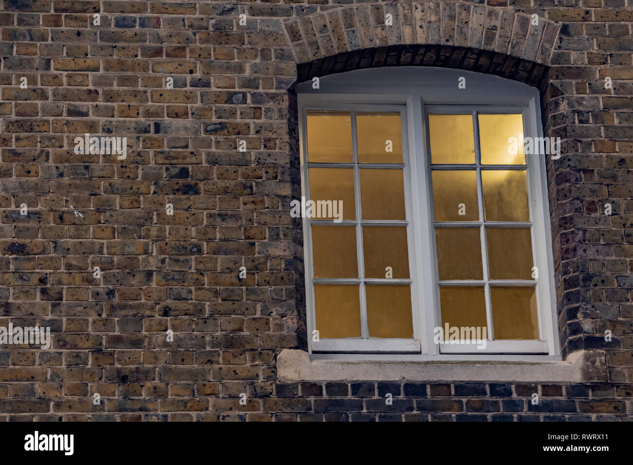 Light shining through the sash window at night. Brick wall facade Stock ...