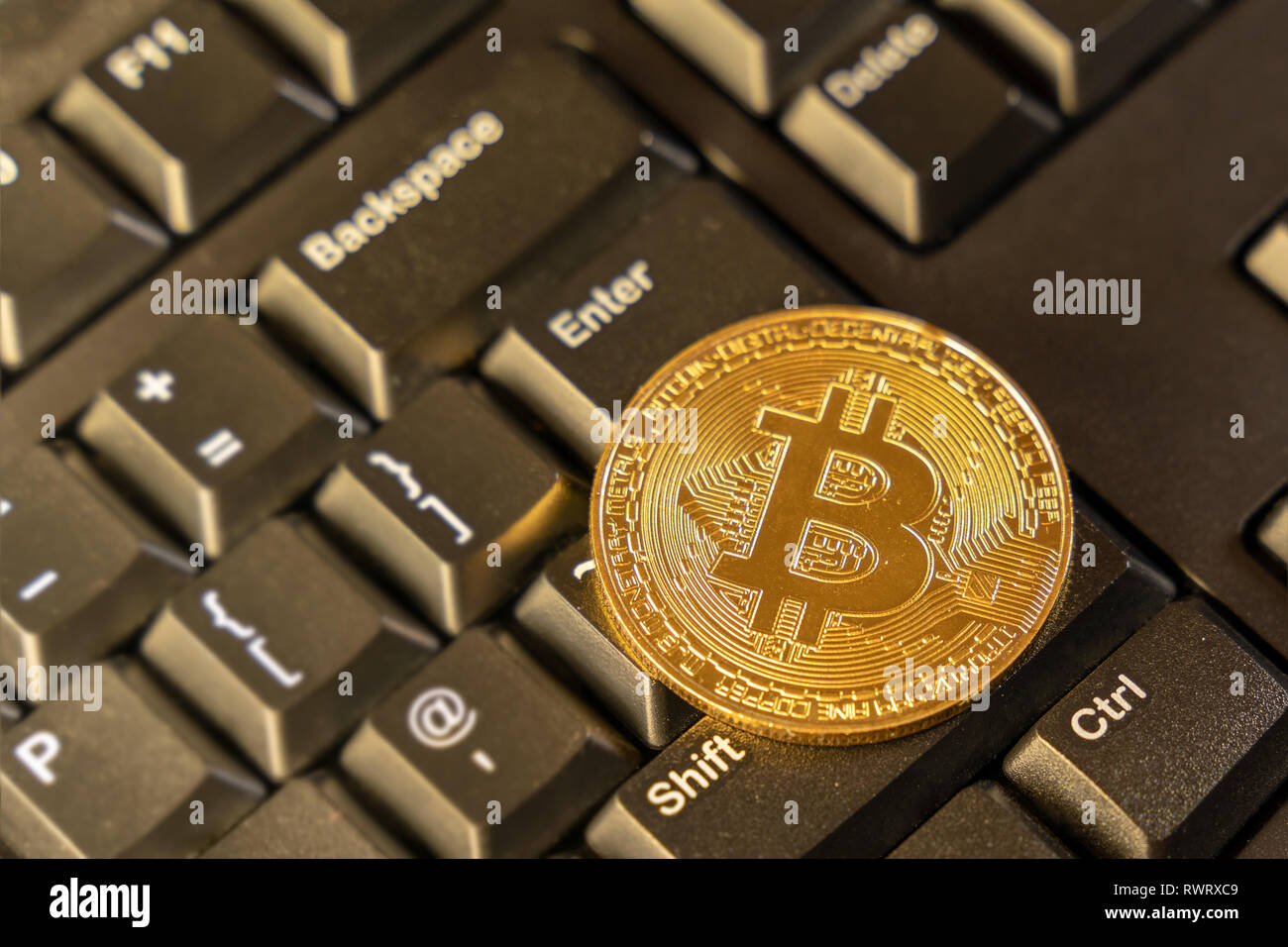 Cryptocurrency coin on top of computer keyboard at background ...
