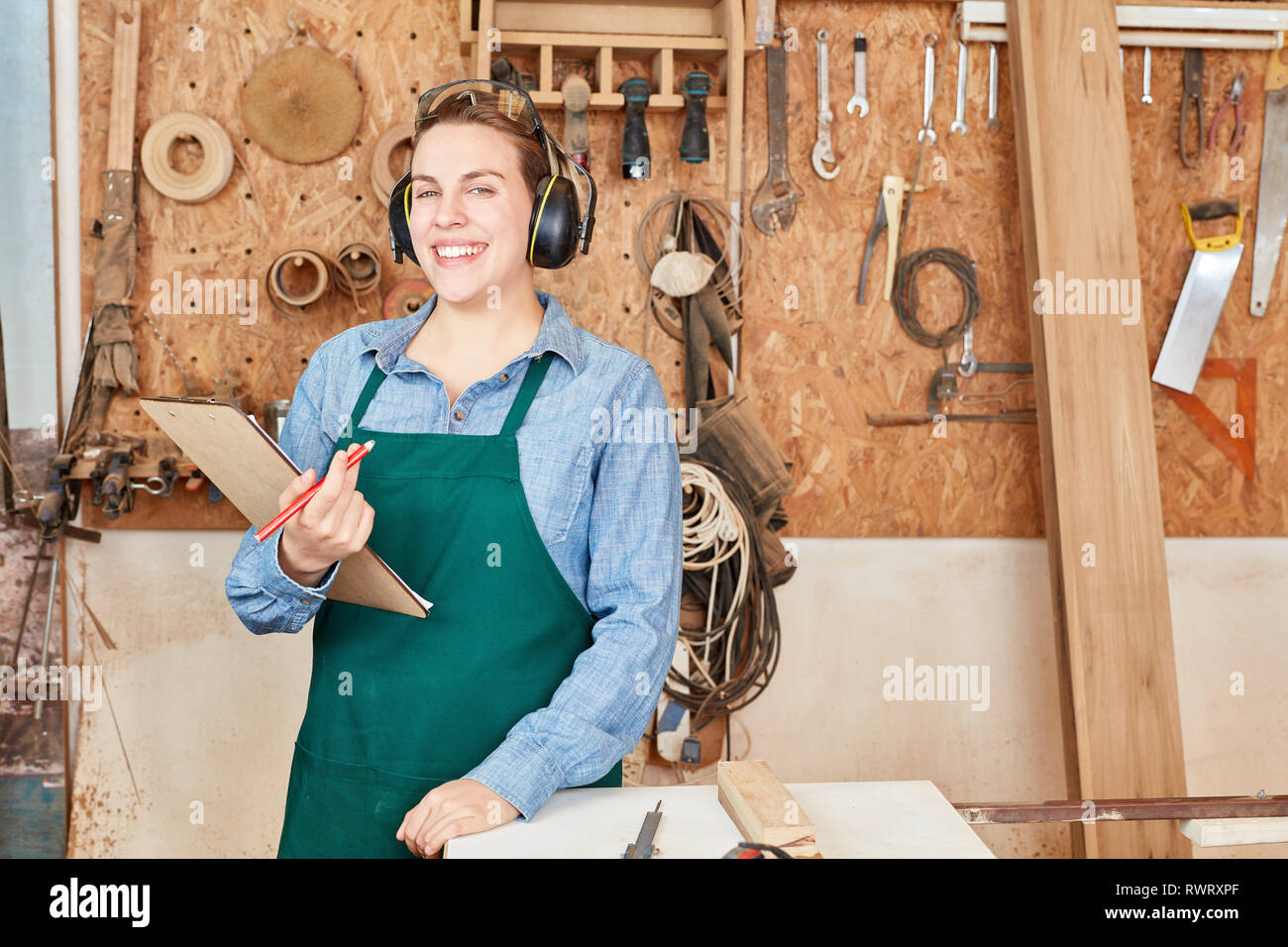 Young woman with checklist as a carpenter. Apprentice in training in ...