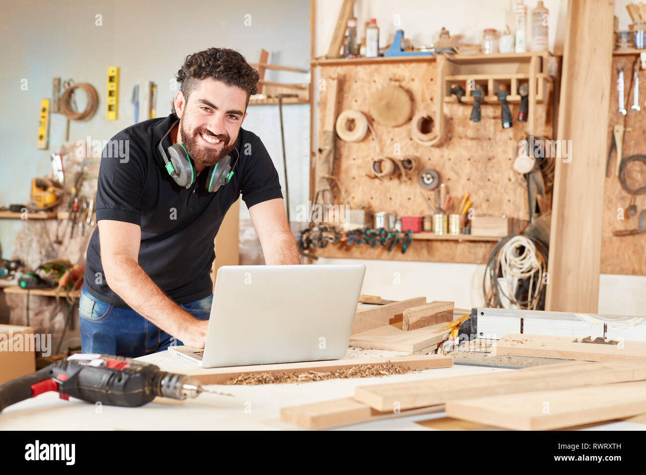Young man as start-up founder of a craft company working on laptop ...