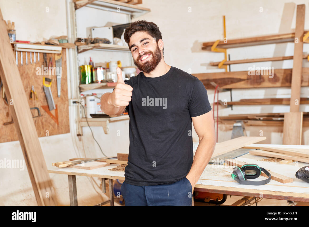 Young man as start-up founder keeps his thumbs up in the joiner's ...