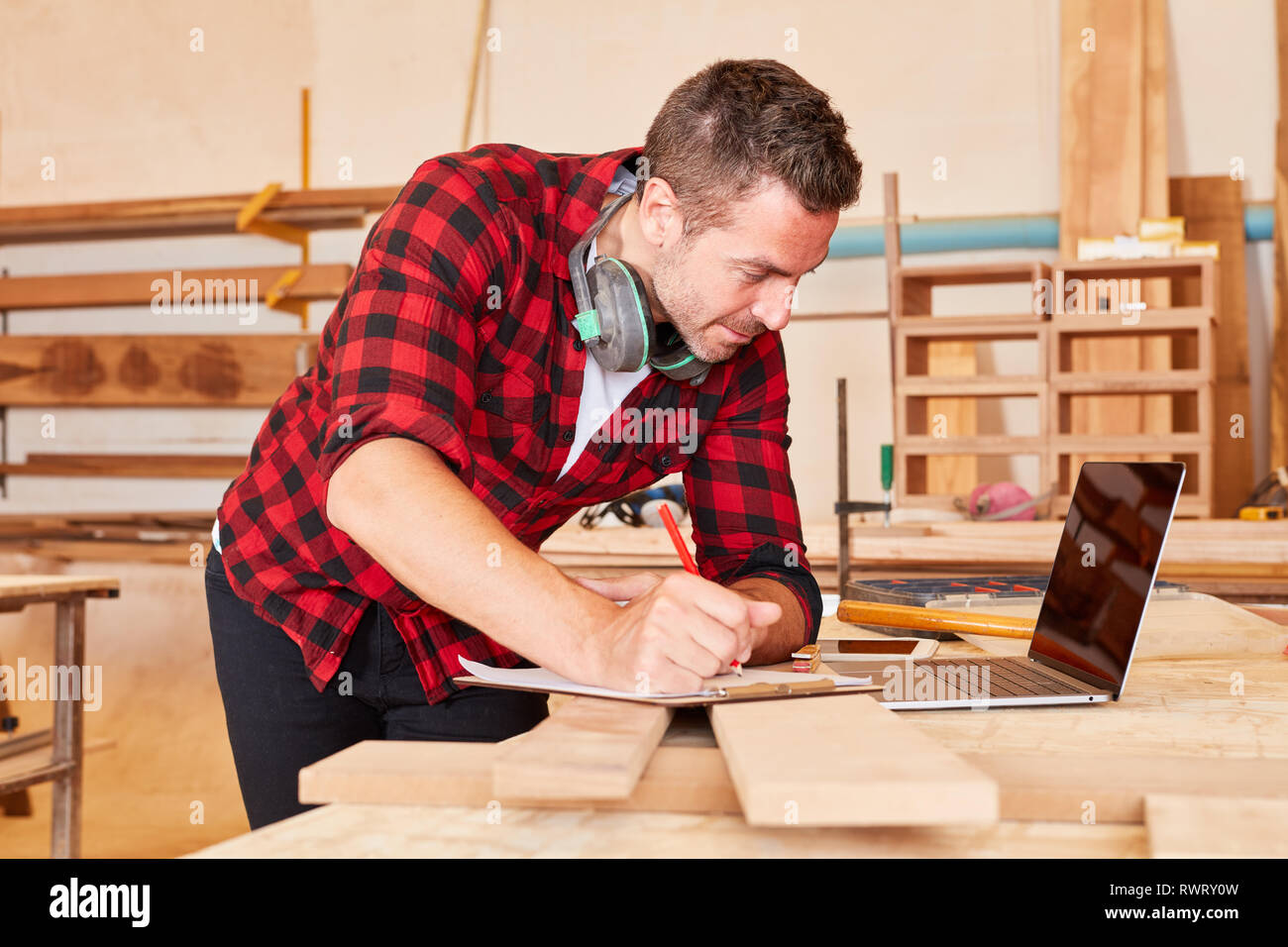 Craftsman with clipboard in the workshop at the laptop Computer at the ...