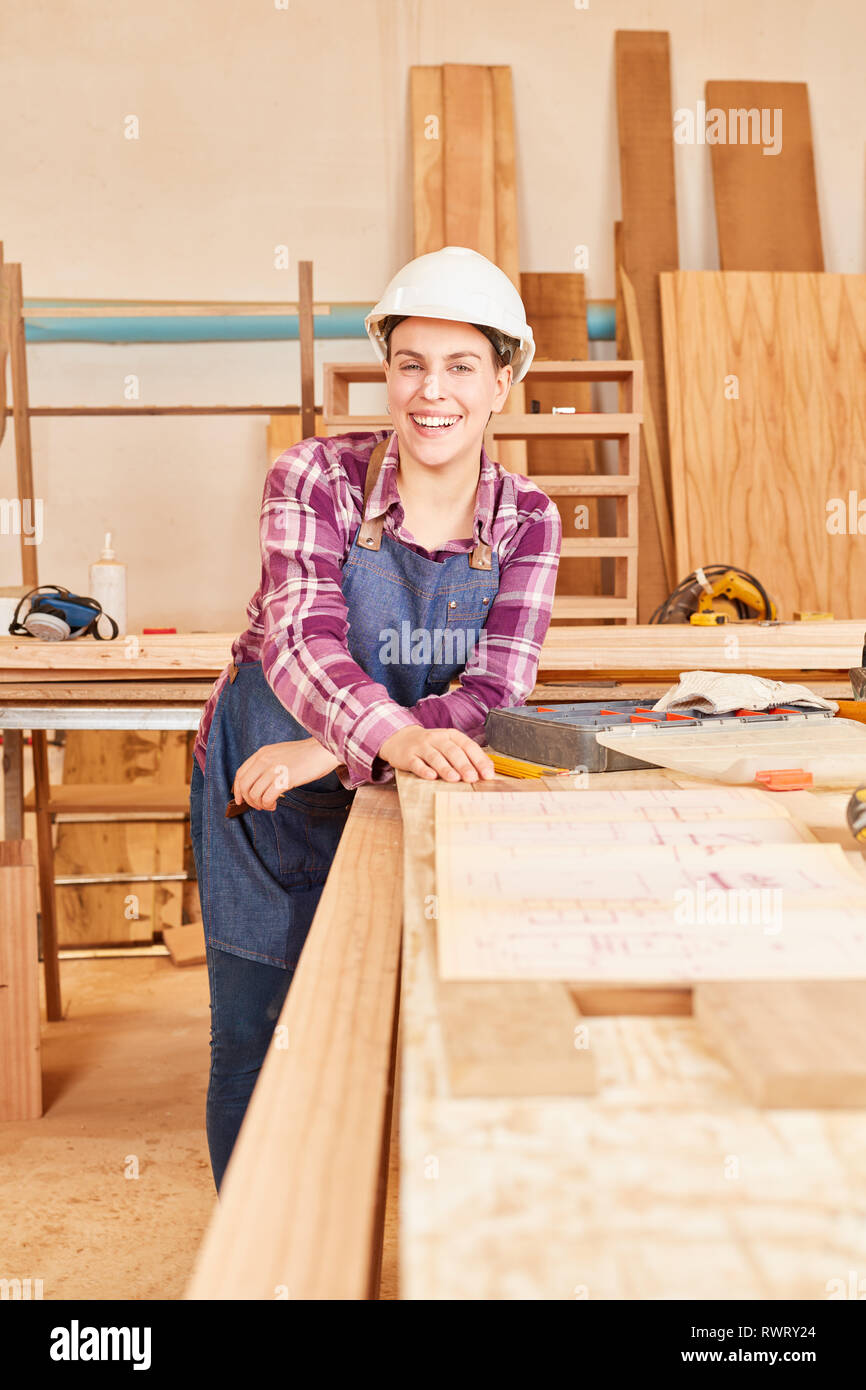 Happy young woman with blueprint and helmet as a craftsman apprentice ...