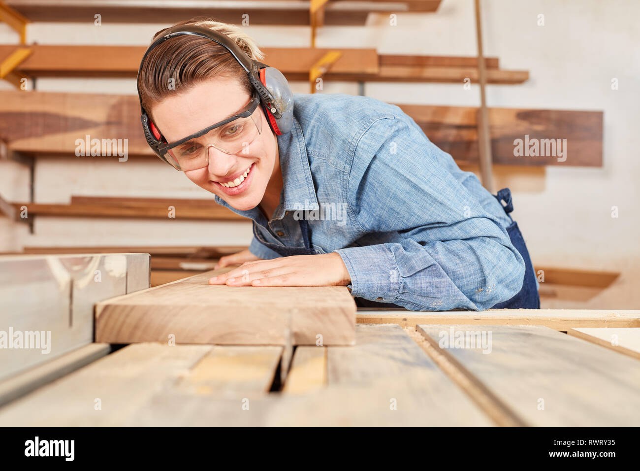 Young woman as joiner trainee works with wood on a circular saw in the ...
