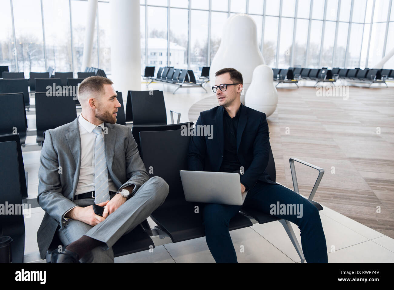 Businessmen working together on laptop in airport lounge Stock Photo ...