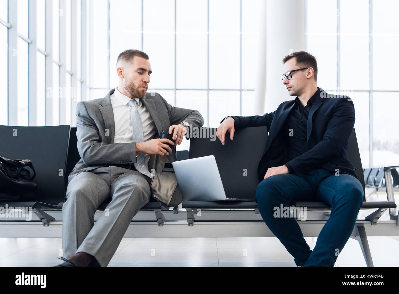 Businessmen working together on laptop in airport lounge Stock Photo ...