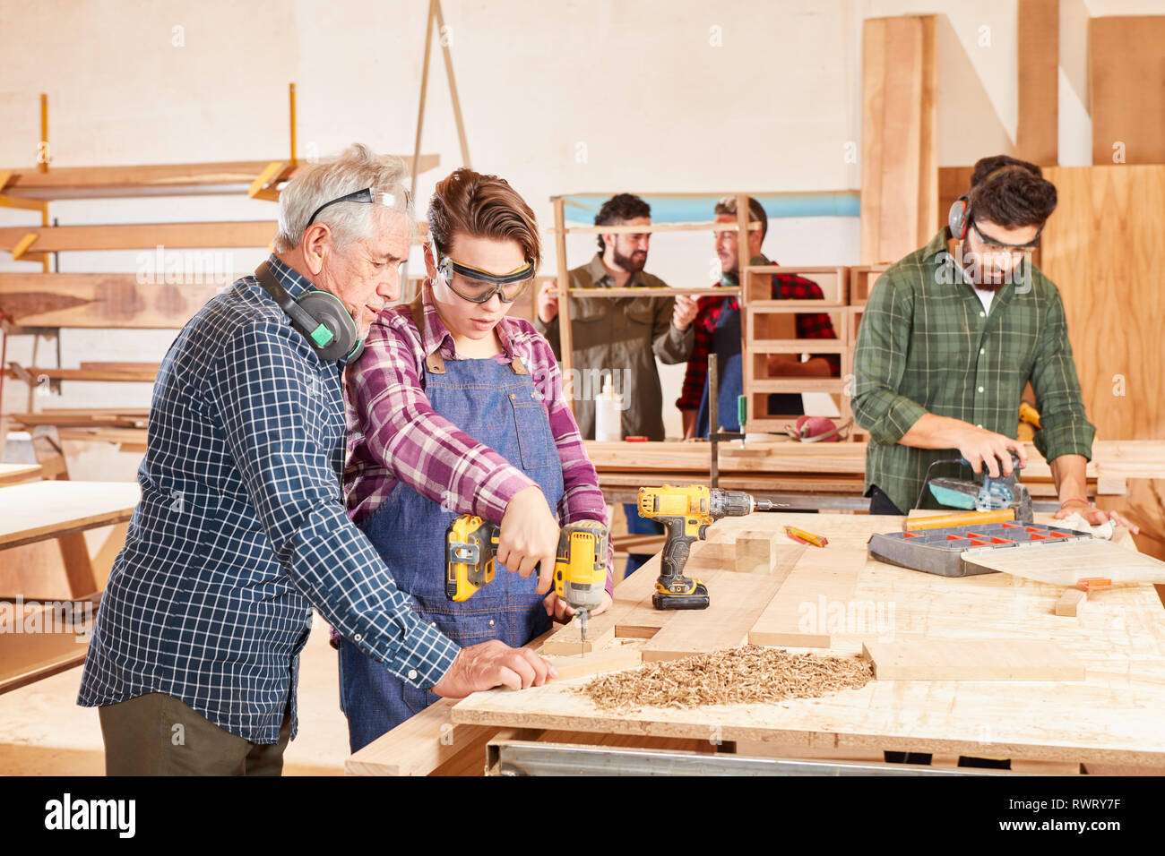 Master and wife apprentice with drill at woodworking workshop Stock ...