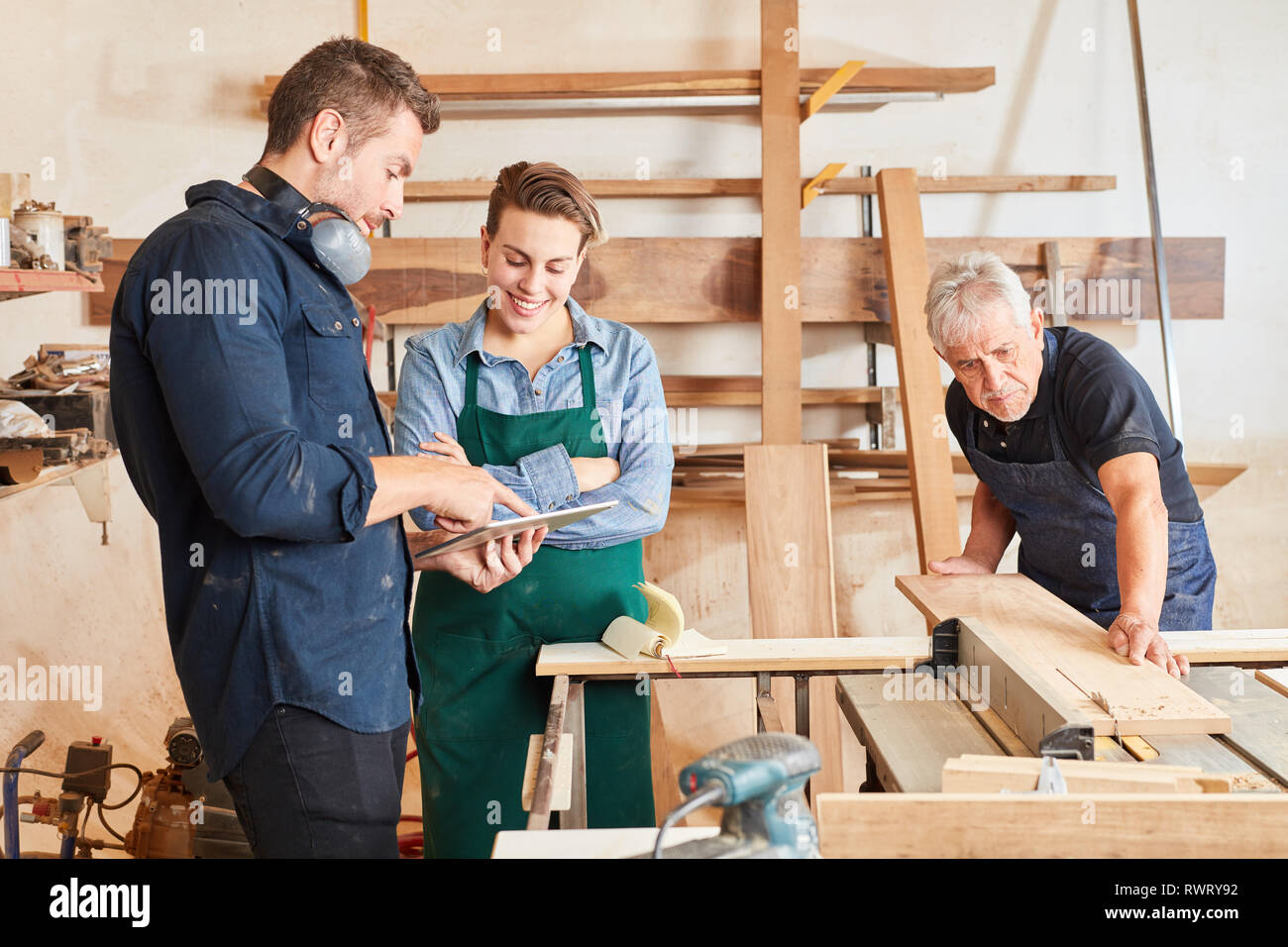 Craftsman team with trainee works together in the workshop with tablet ...