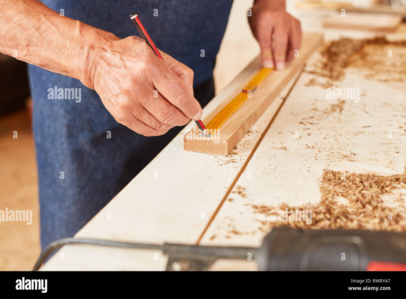 Hand of the craftsman with precise measuring with pencil and a folding ...