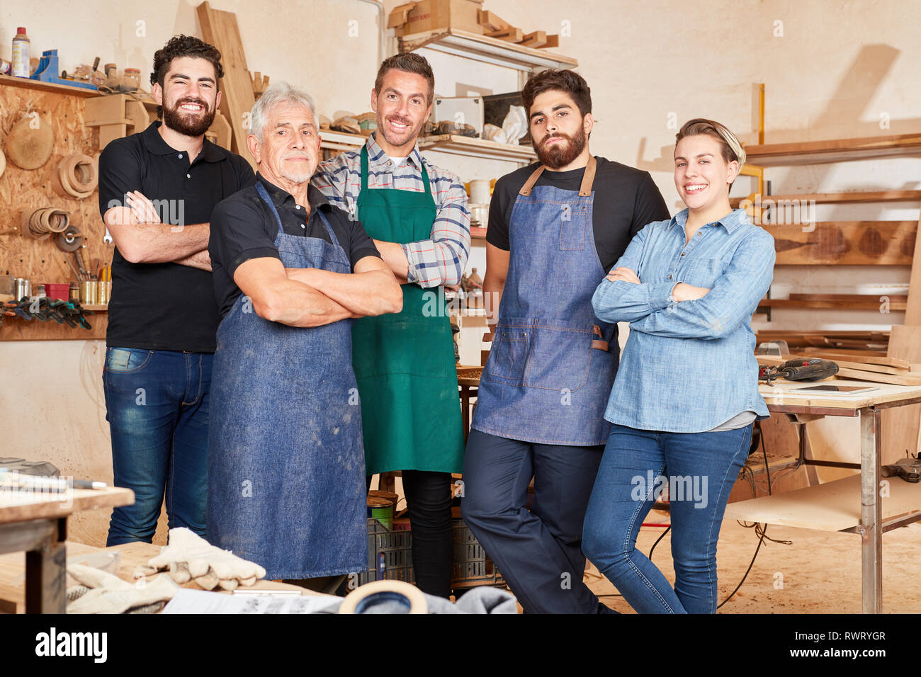 Group craftsmen with trainees as a confident team with crossed arms ...