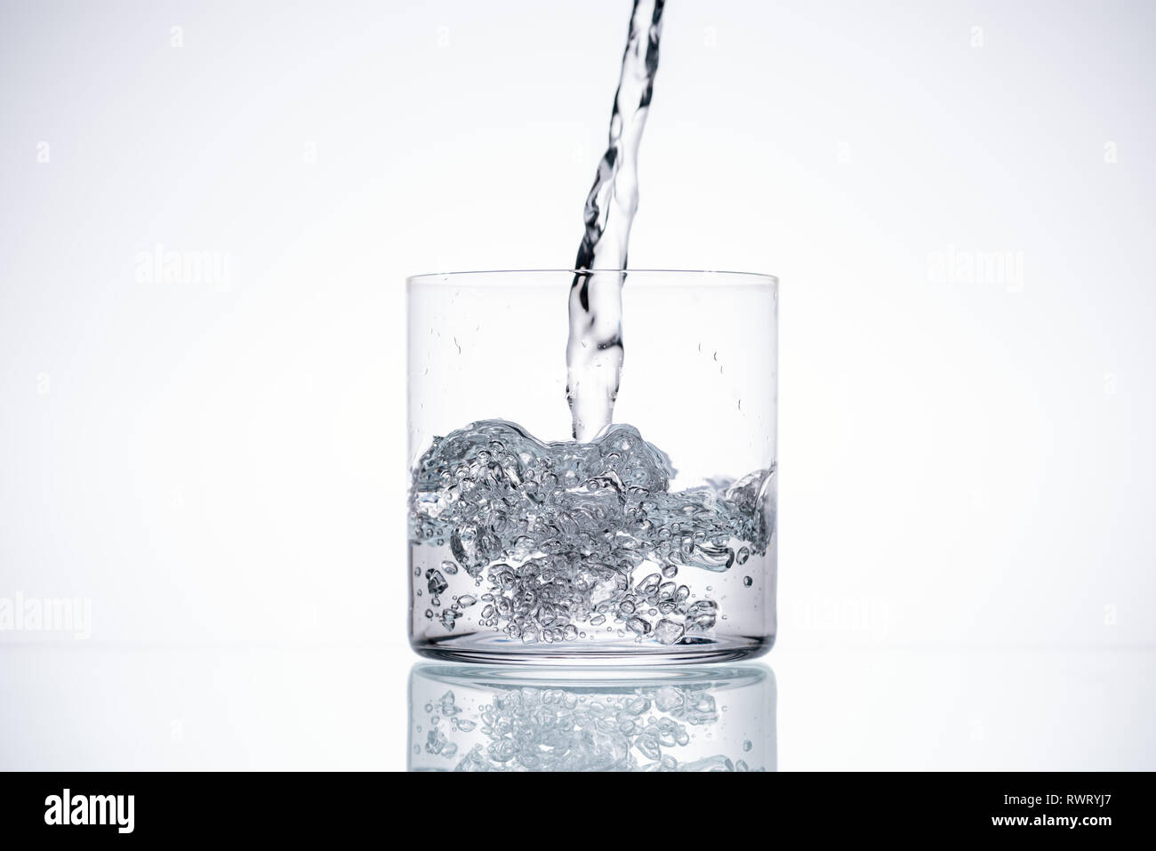 water pouring in glass on white background with backlit and copy space ...
